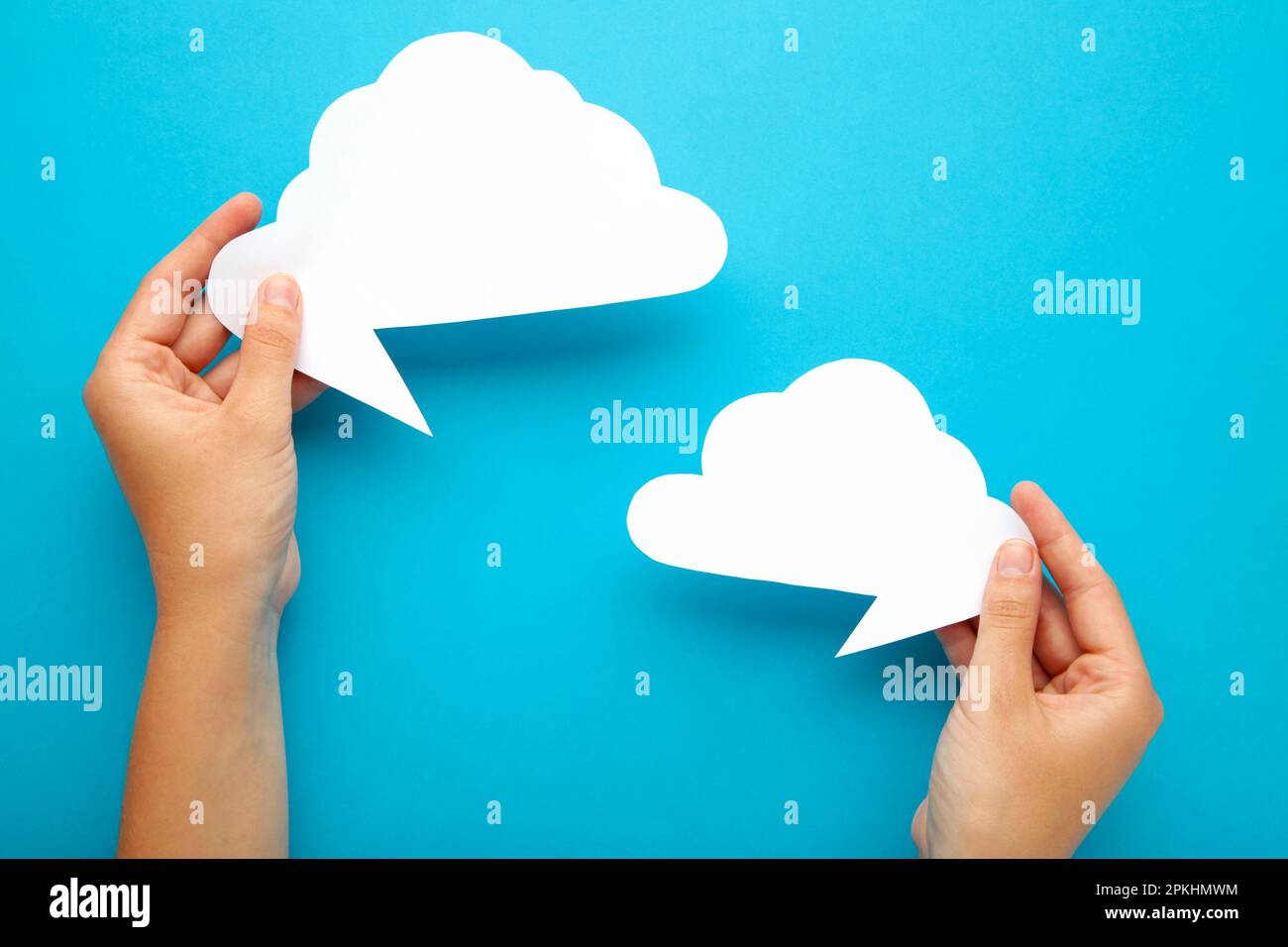Two hands holding up speech bubbles on blue. Top view Stock Photo - Alamy