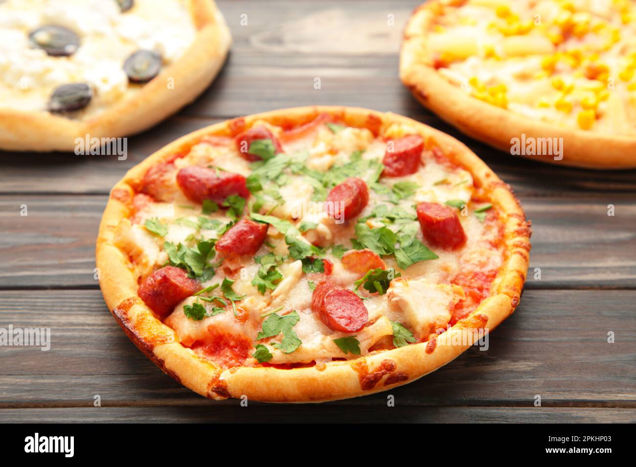 Three different kinds of pizzas on brown wooden table with copy space ...