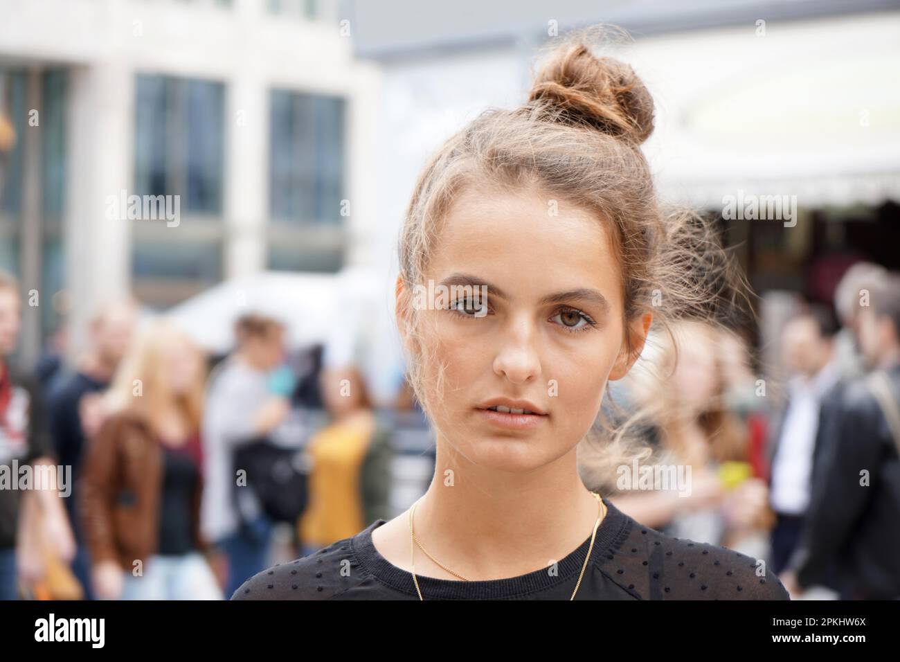 young woman downtown in a pedestrian area with blurred people in the ...