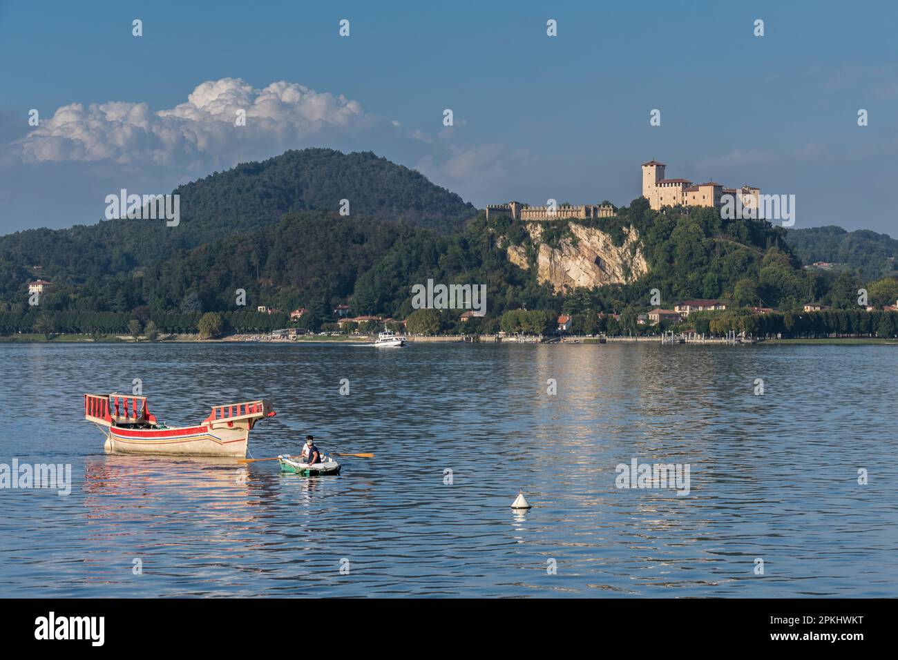 Rowing boat pulling a traditional boat on Lake Maggiore Piedmont Italy ...