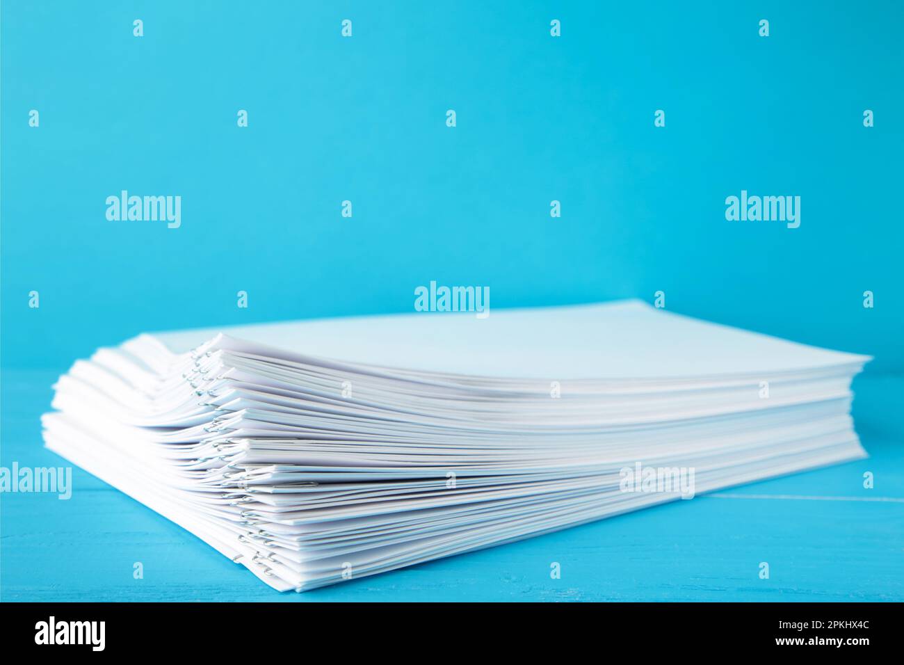 Colorful paper clip with pile of overload white paperwork on blue. Top ...