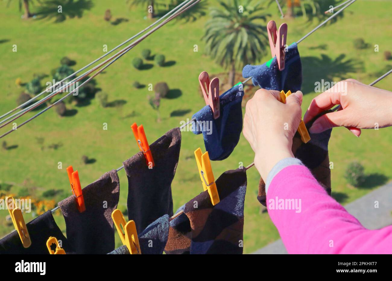 Closeup woman's hand hanging socks on clothesline with clothespins on ...