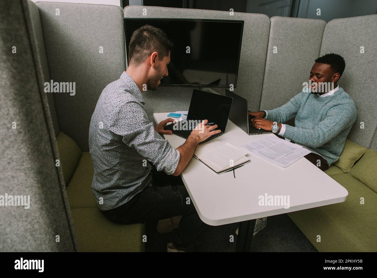 Black and white male teammates having a conversation while working ...