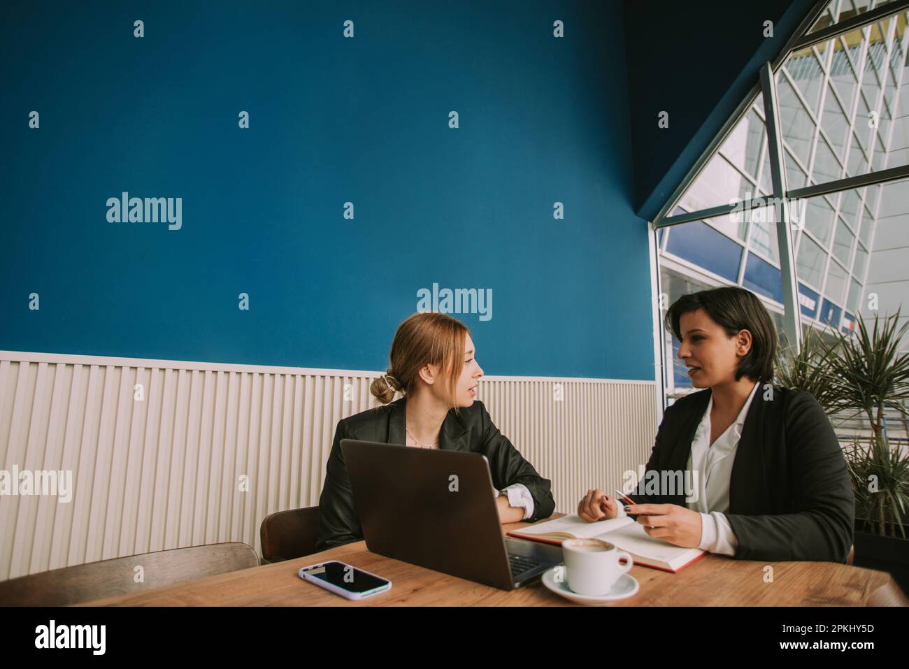 Two business women talking at the office while sitting with the ...