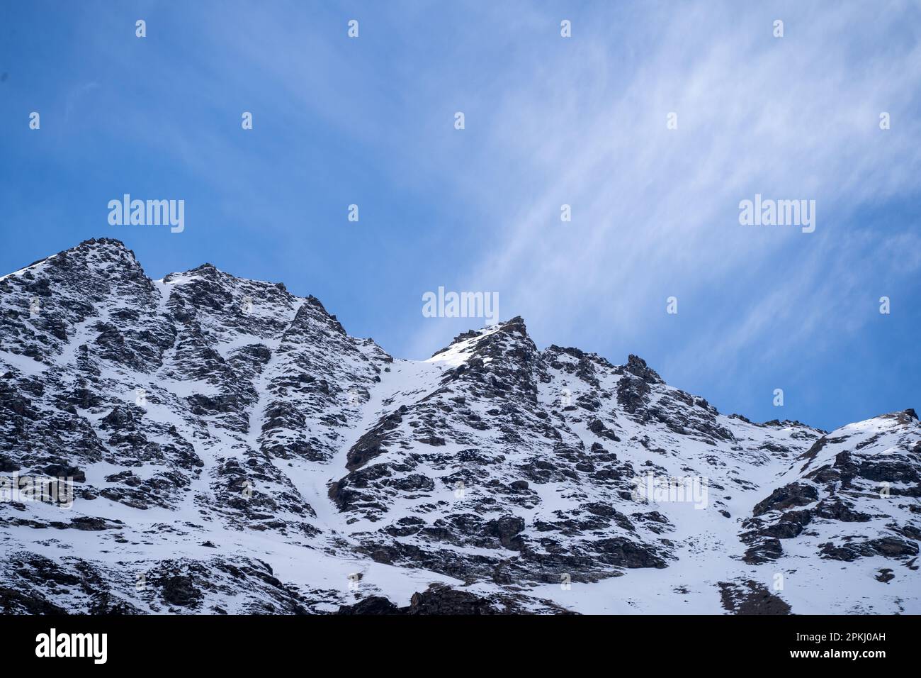white wispy clouds moving over snow covered rocky himalaya mountains in ...