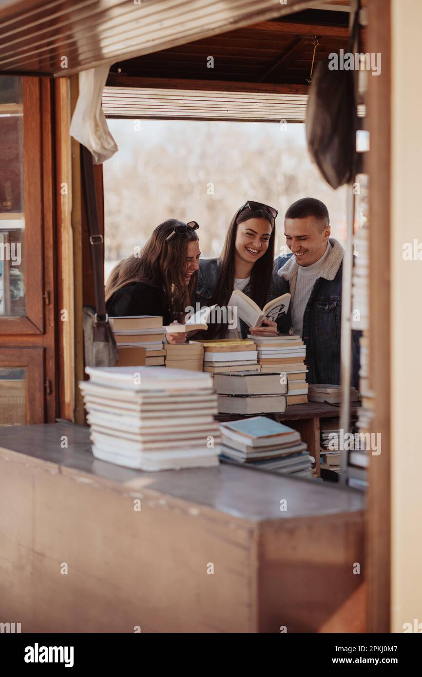 Three close friends laughing while standing at the book store and ...