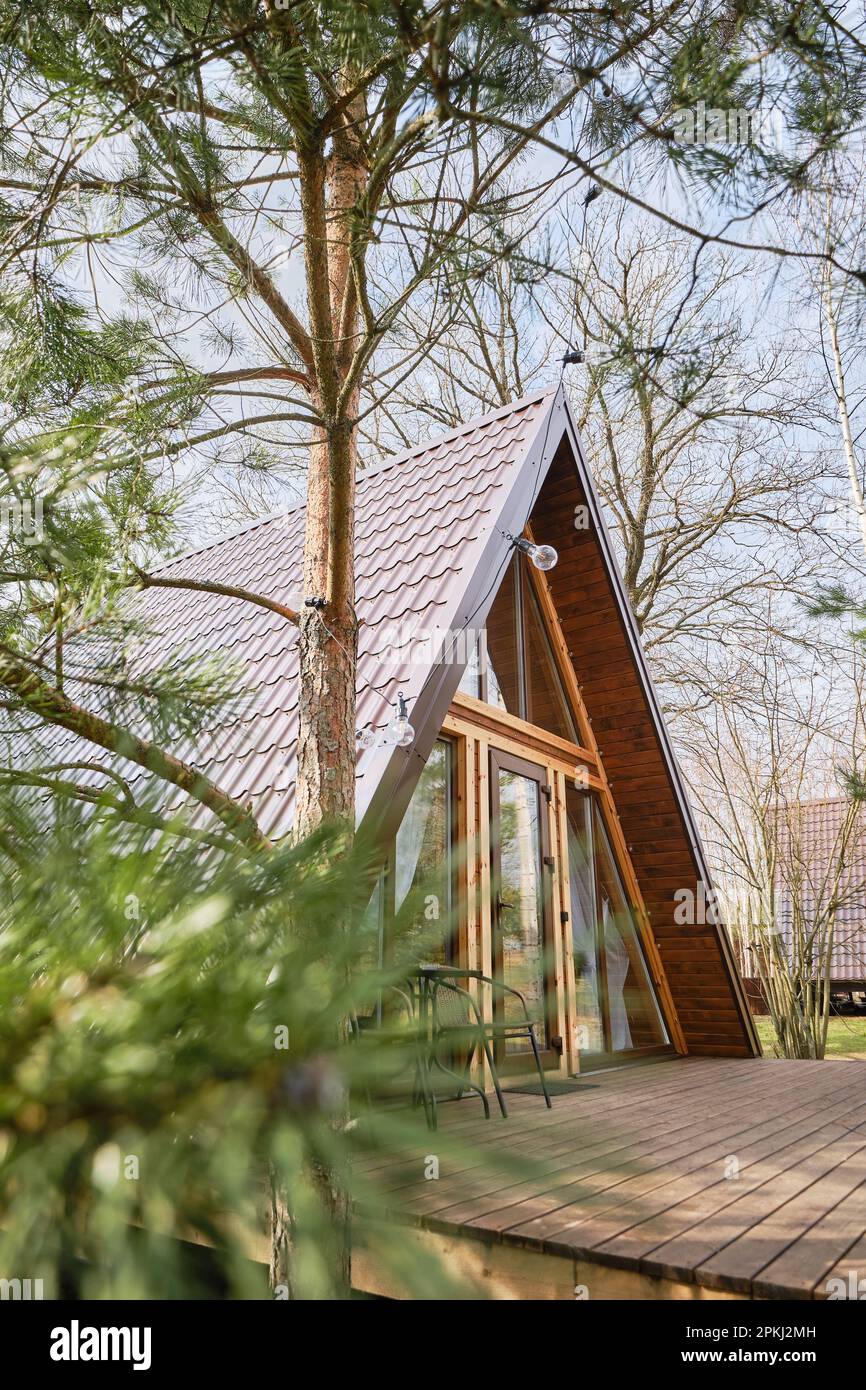 A-frame wooden chalet with a blurred pine tree on foreground Stock ...