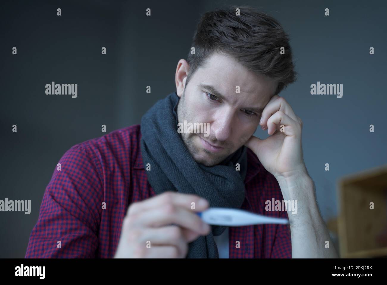 Sick unhealthy German man office worker looking at thermometer, suffer ...
