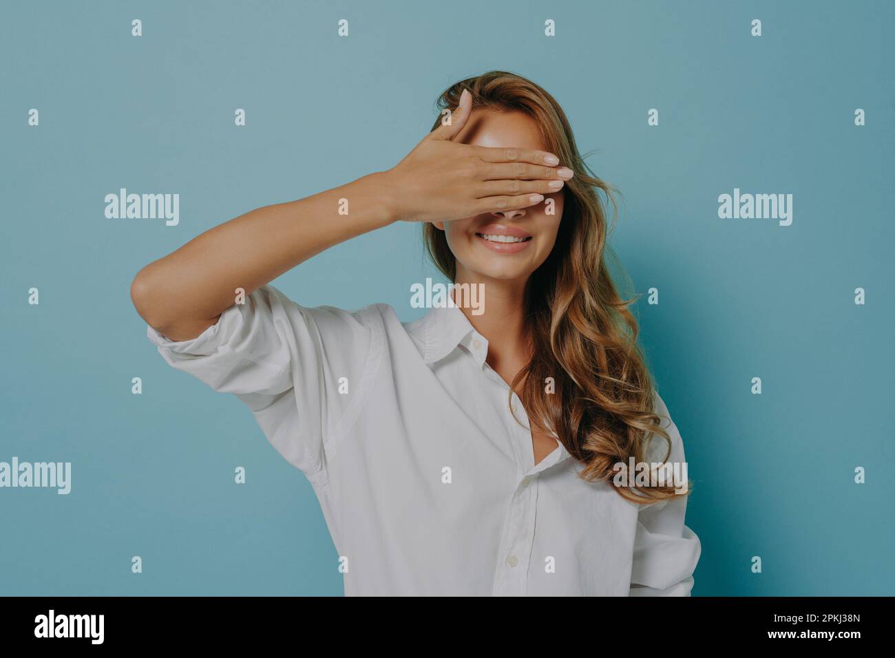 Portrait of cheerful young woman broadly smiling while covering her ...