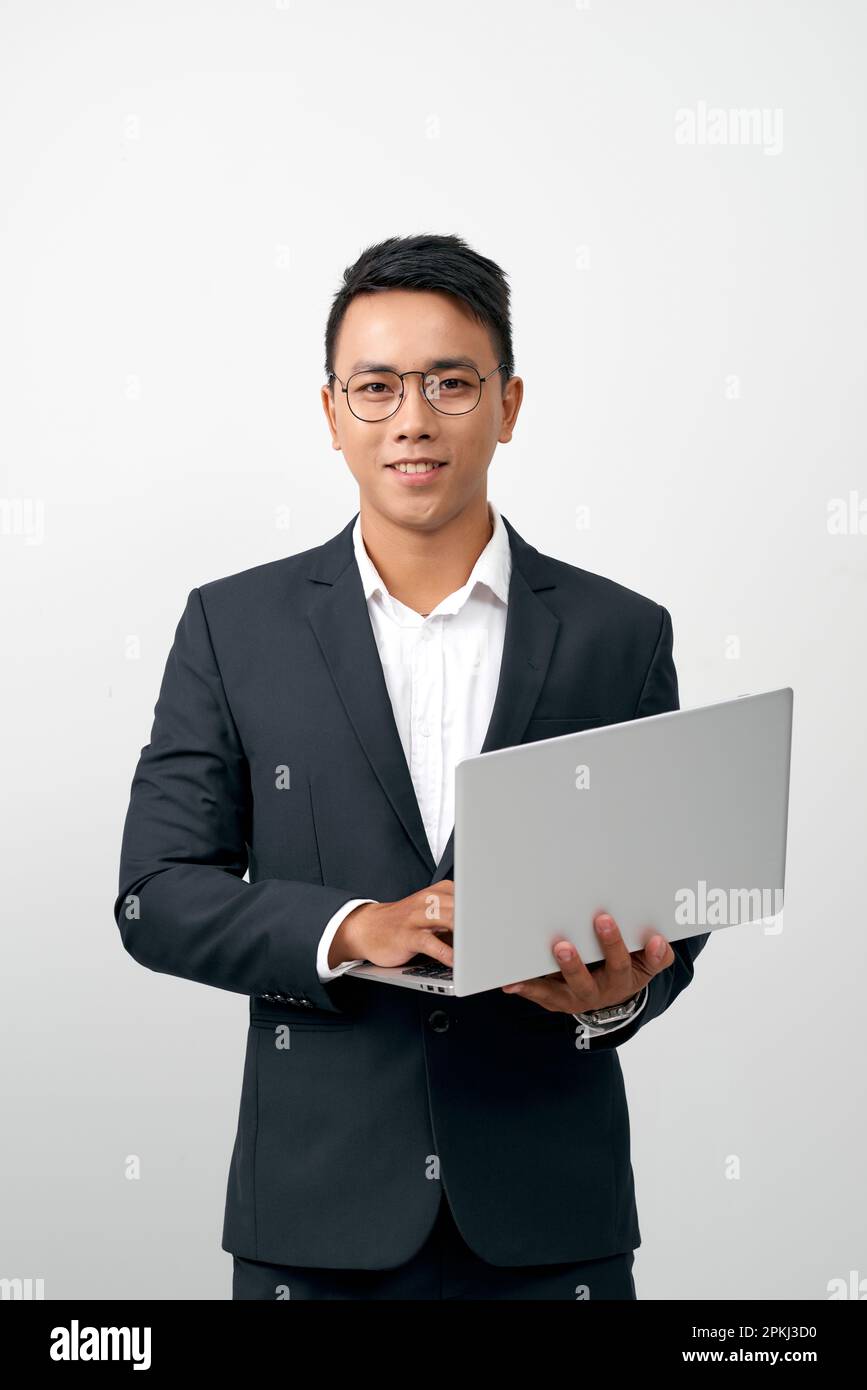 Portrait of smiling handsome young businessman in formal suit holding an open laptop in hand ...