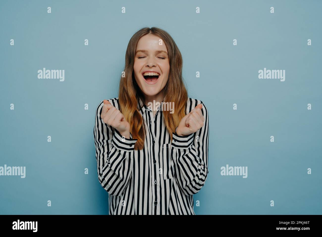 Laughing teenage girl wearing in shirt with clenched fists screaming ...
