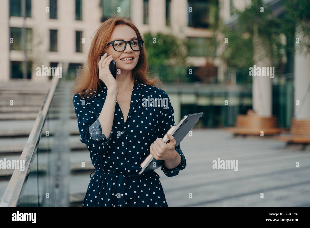 Positive redhead European woman has telephone conversation while ...