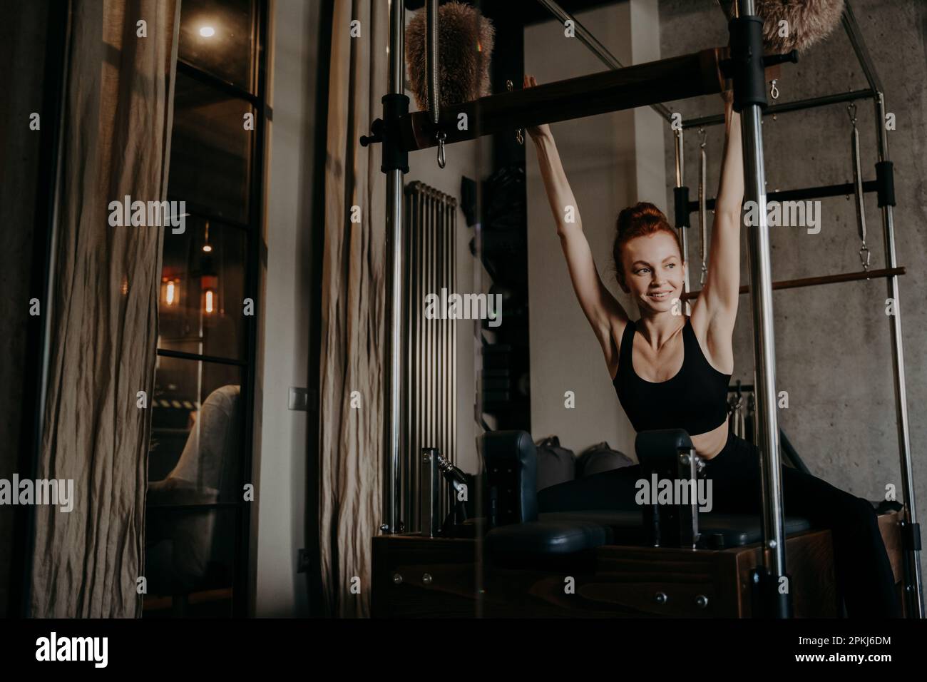 Happy healthy woman in black sportswear stretching upper body pulling ...