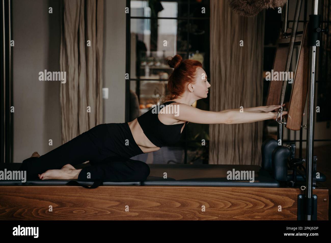 Side view of flexible red haired female pilates instructor realizing ...