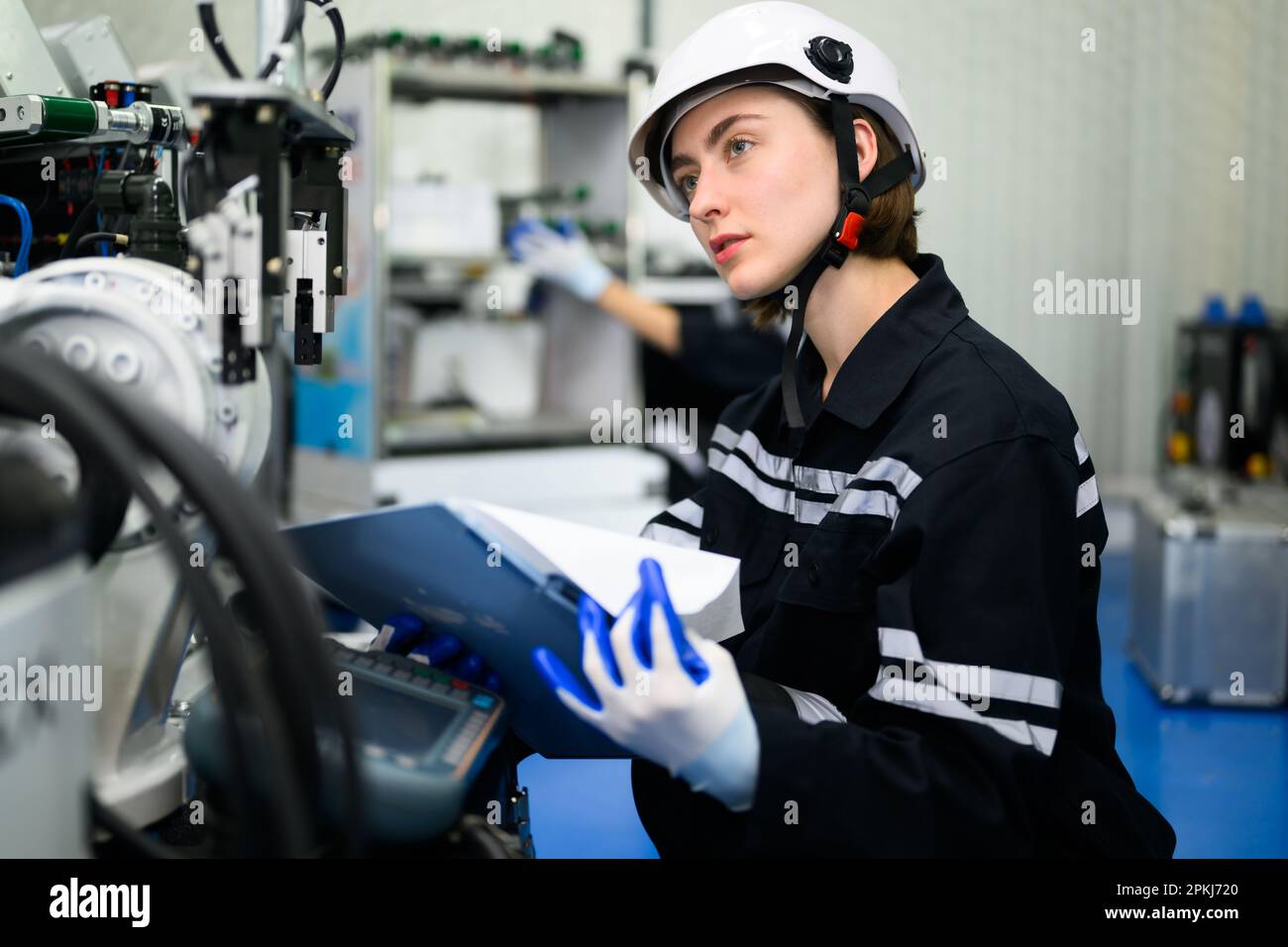 Professional female engineer with robotic machine at factory Stock ...