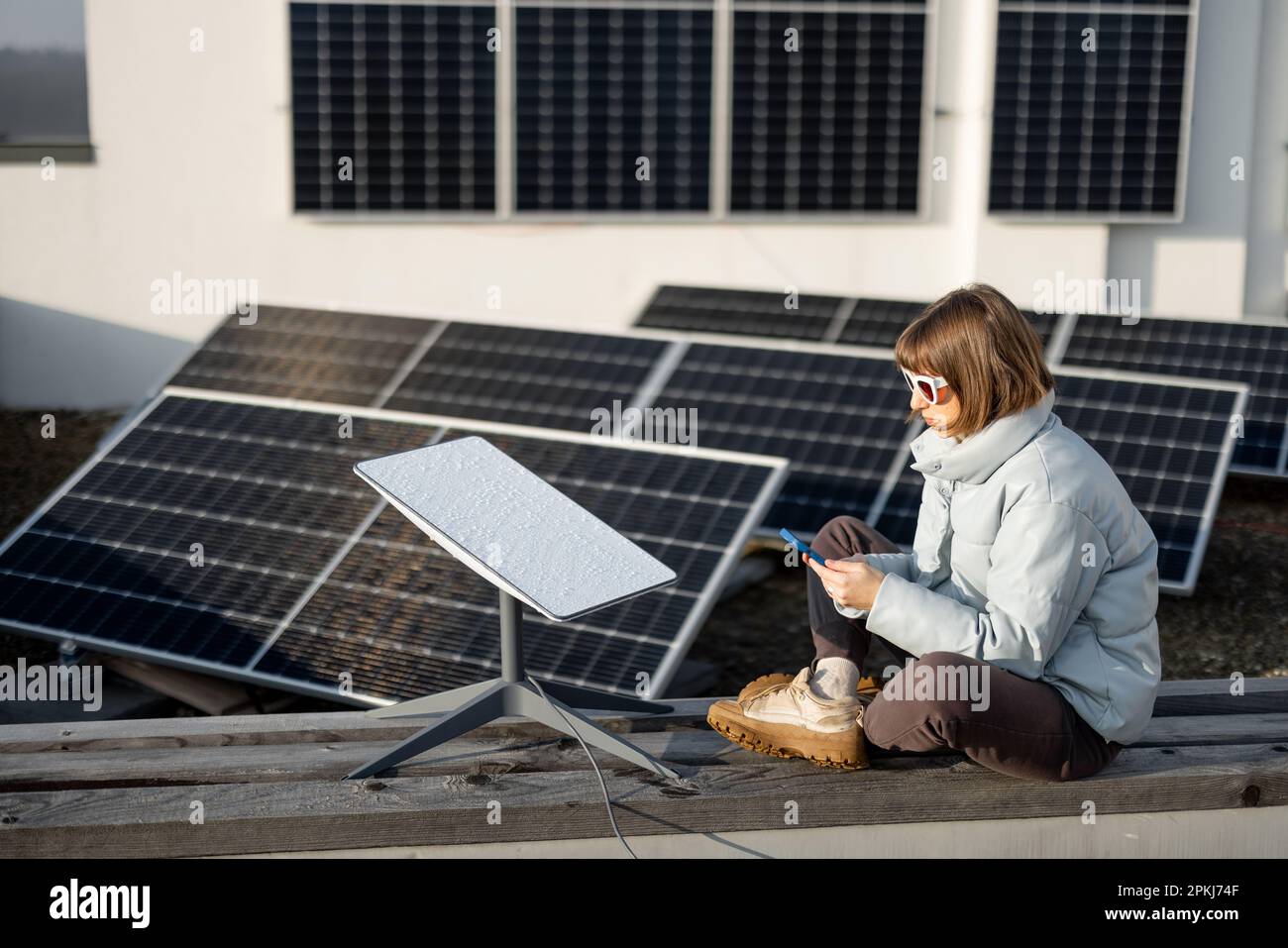Woman uses Starlink Internet on roof with solar panels Stock Photo - Alamy