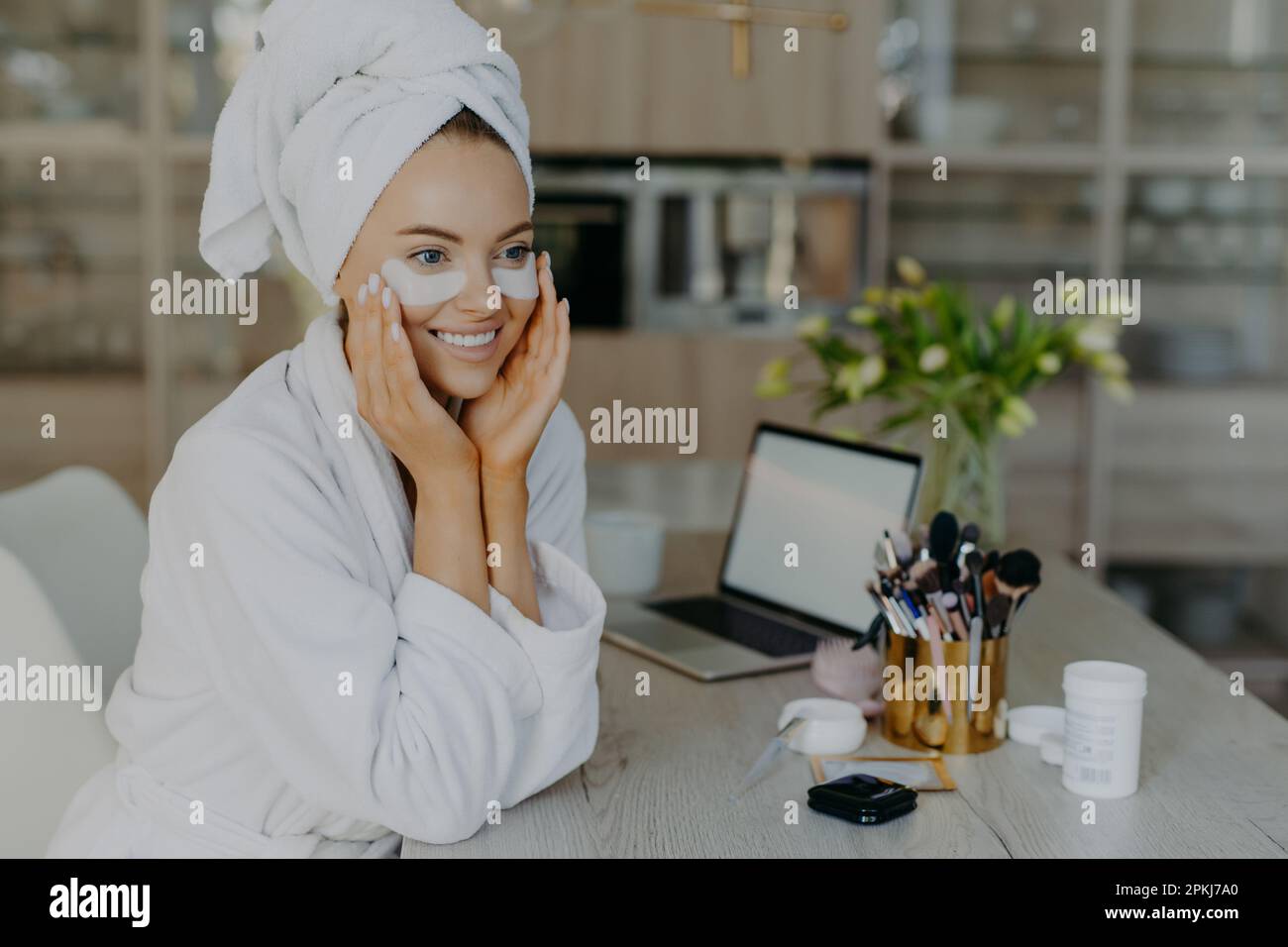 Pretty smiling young female model applies collagen patches under eyes ...