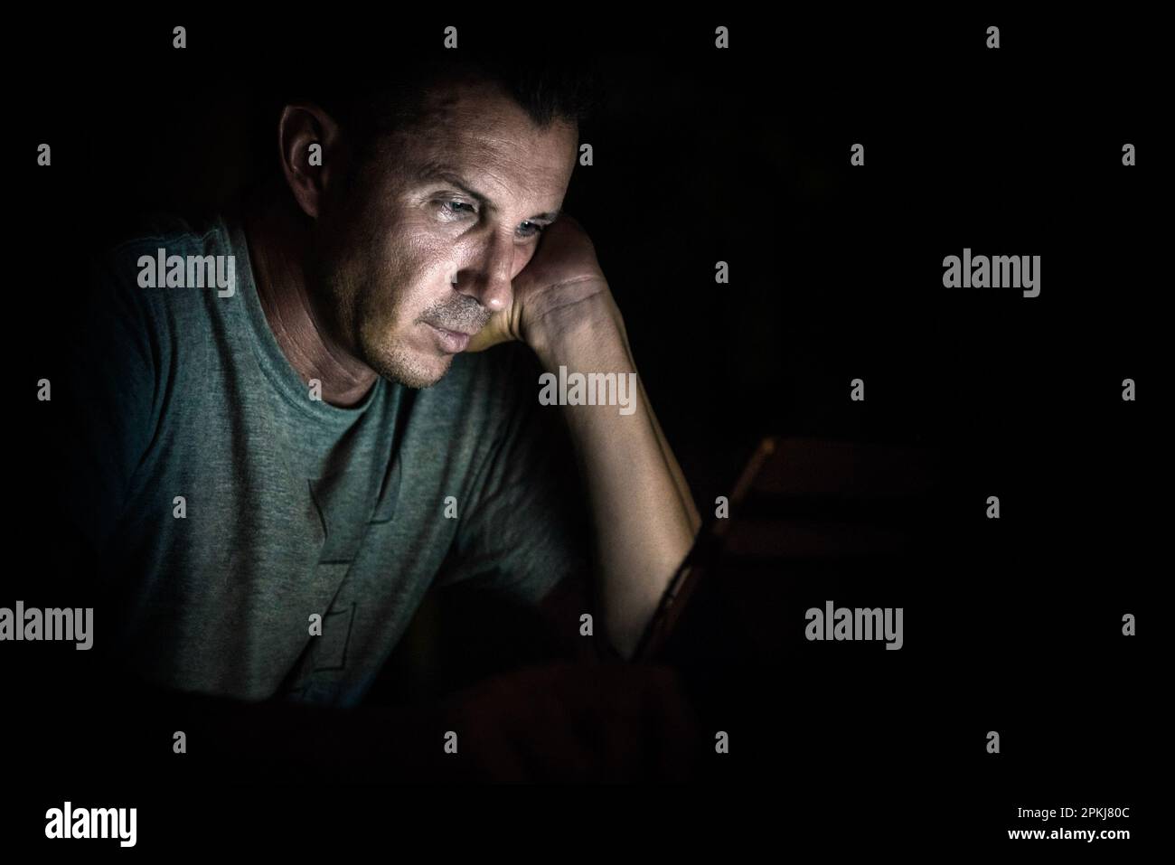 Young handsome man at laptop computer with light reflection from the ...