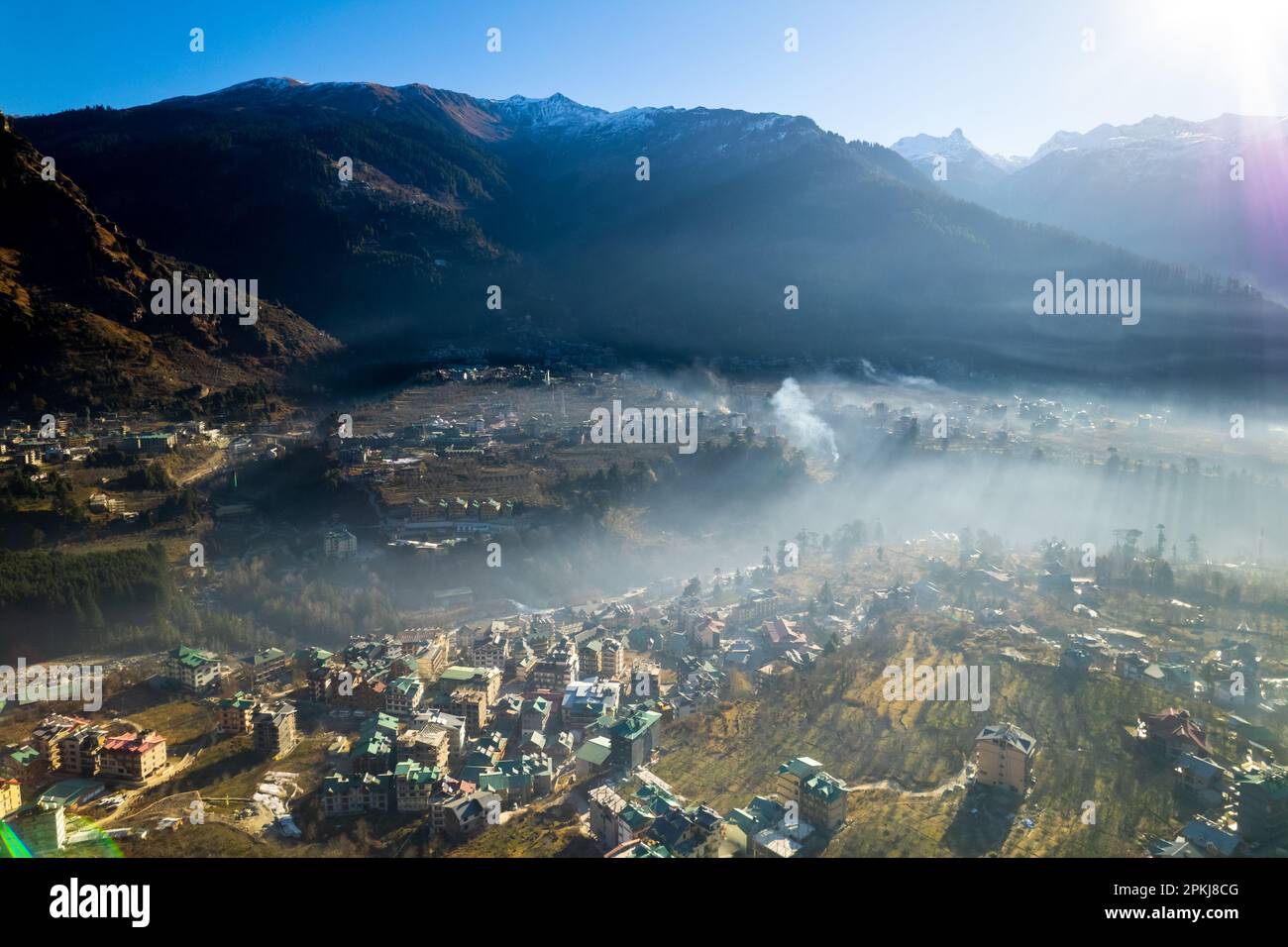 aerial drone shot gaining height over fog covered valley town of manali ...