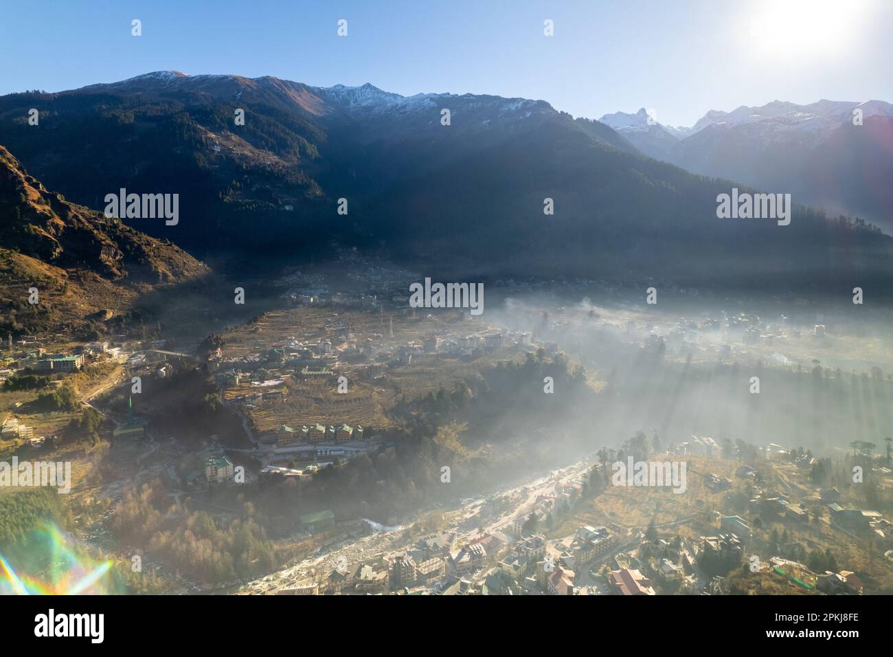 aerial drone shot gaining height over fog covered valley town of manali ...