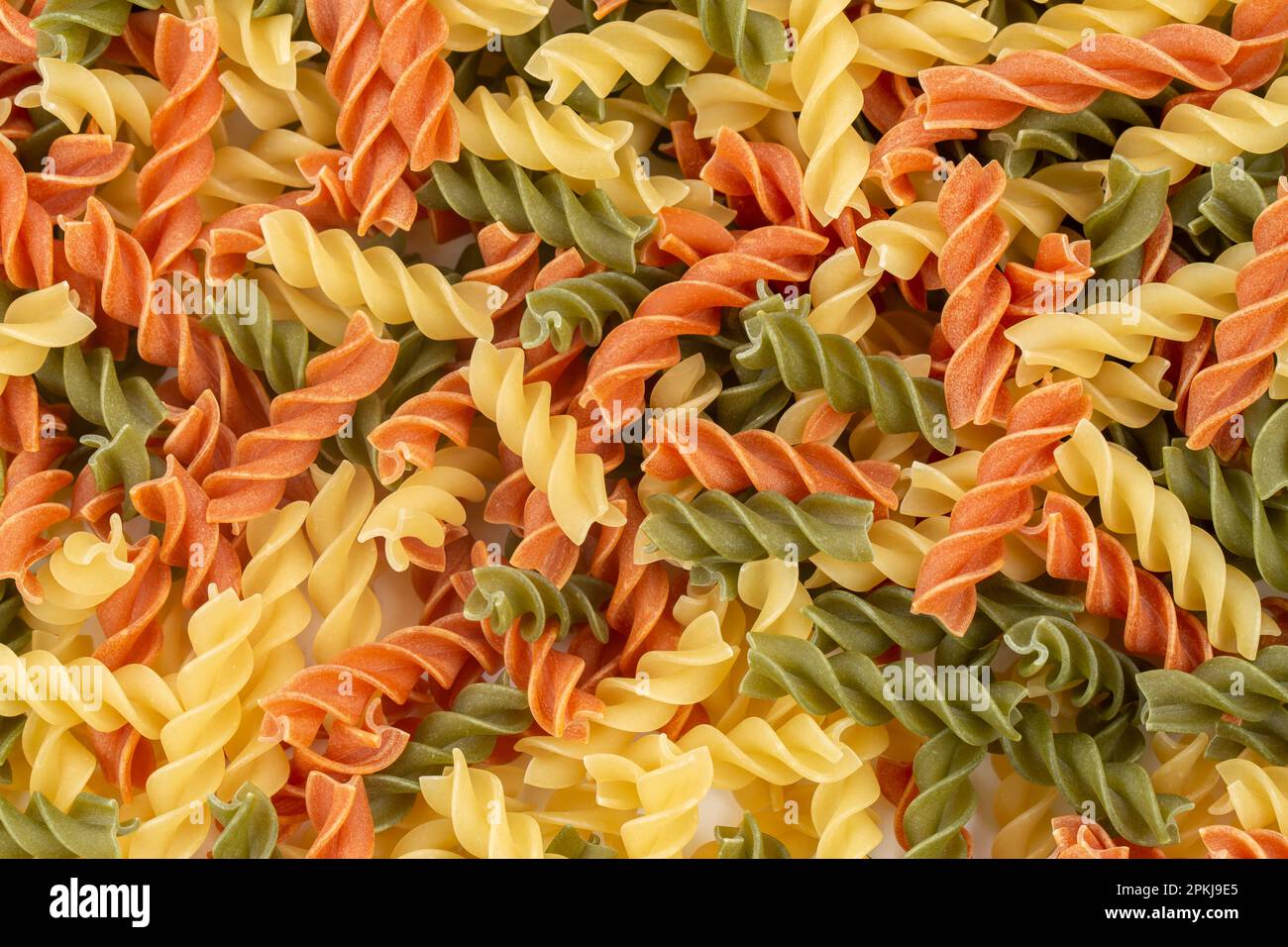 Raw colored pasta fusilli. Uncooked pastas background. Top view Stock ...