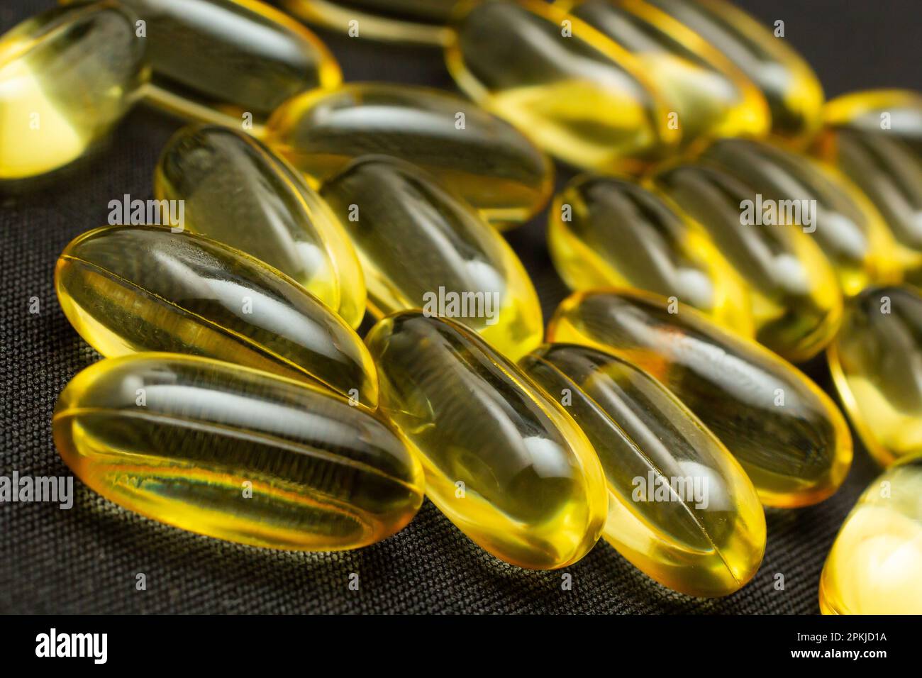 Macro Close up of Omega 3 gel capsule on a reflective black background ...