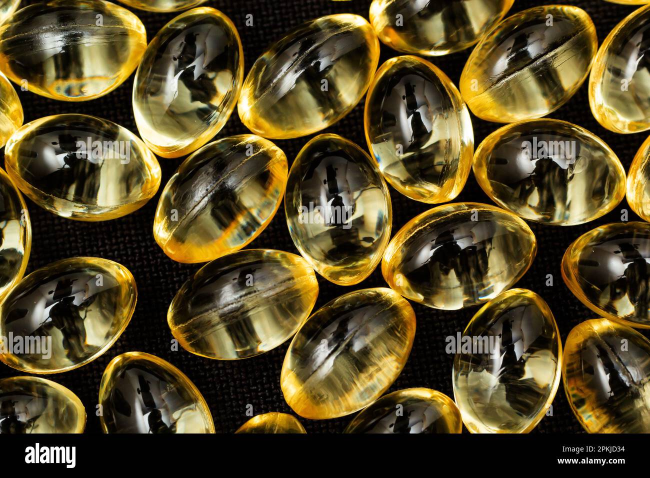 Macro Close up of Omega 3 gel capsule on a reflective black background ...
