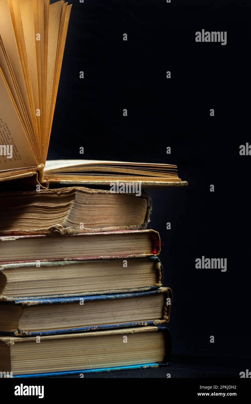 stack of old books with opened one on top on dark background. Old books ...