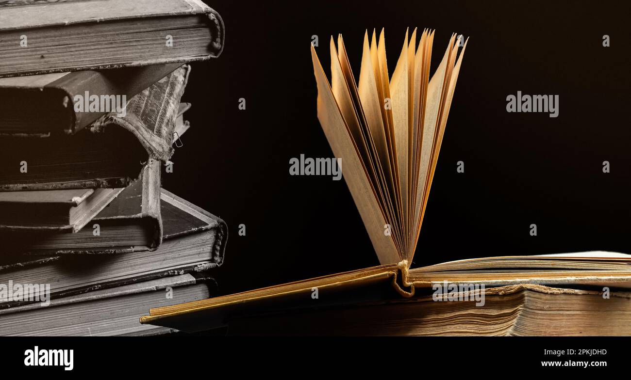 stack of old books with opened one on top on dark background. Old books ...