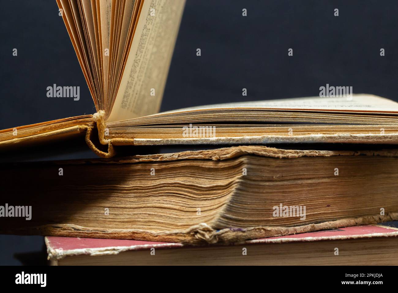 Stack of hardcover old books with an open book on a dark background. Bookshelf shop, Knowledge ...