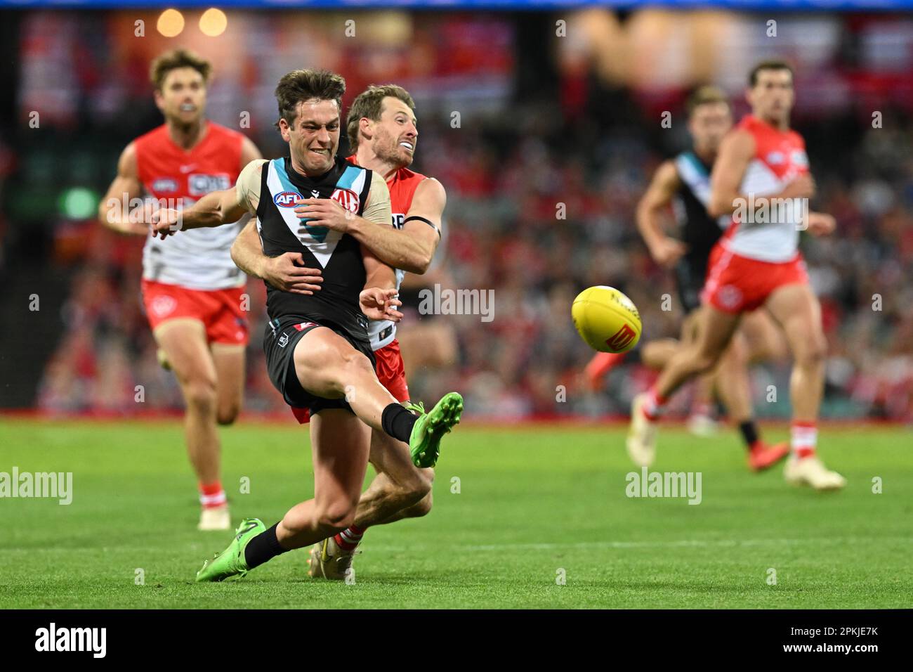 Zak Butters of the Power gets a kick away despite a tackle by Harry Cunningham of the Swans ...