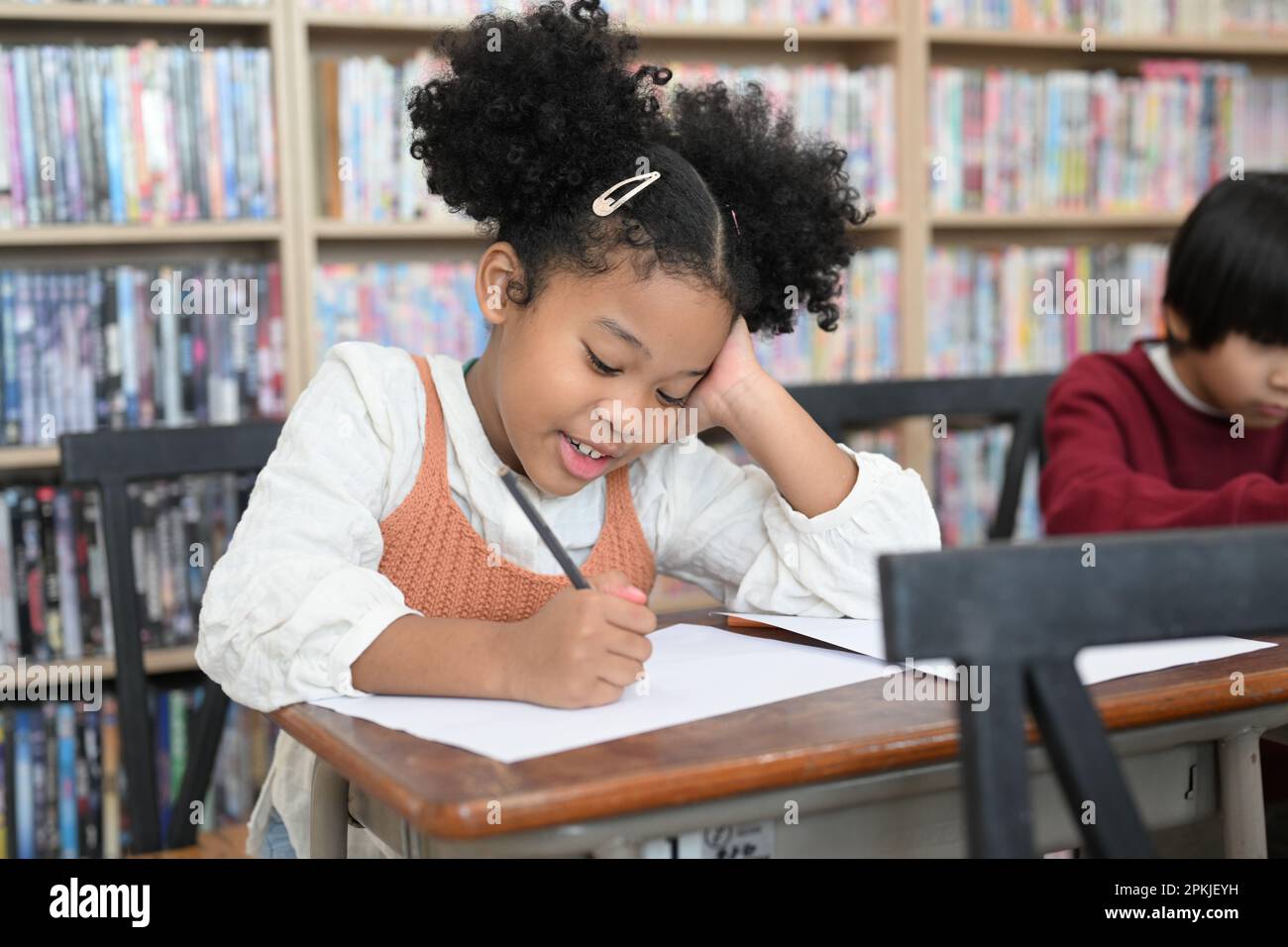 Cute pupils writing and painting on paper at desk in classroom Stock ...