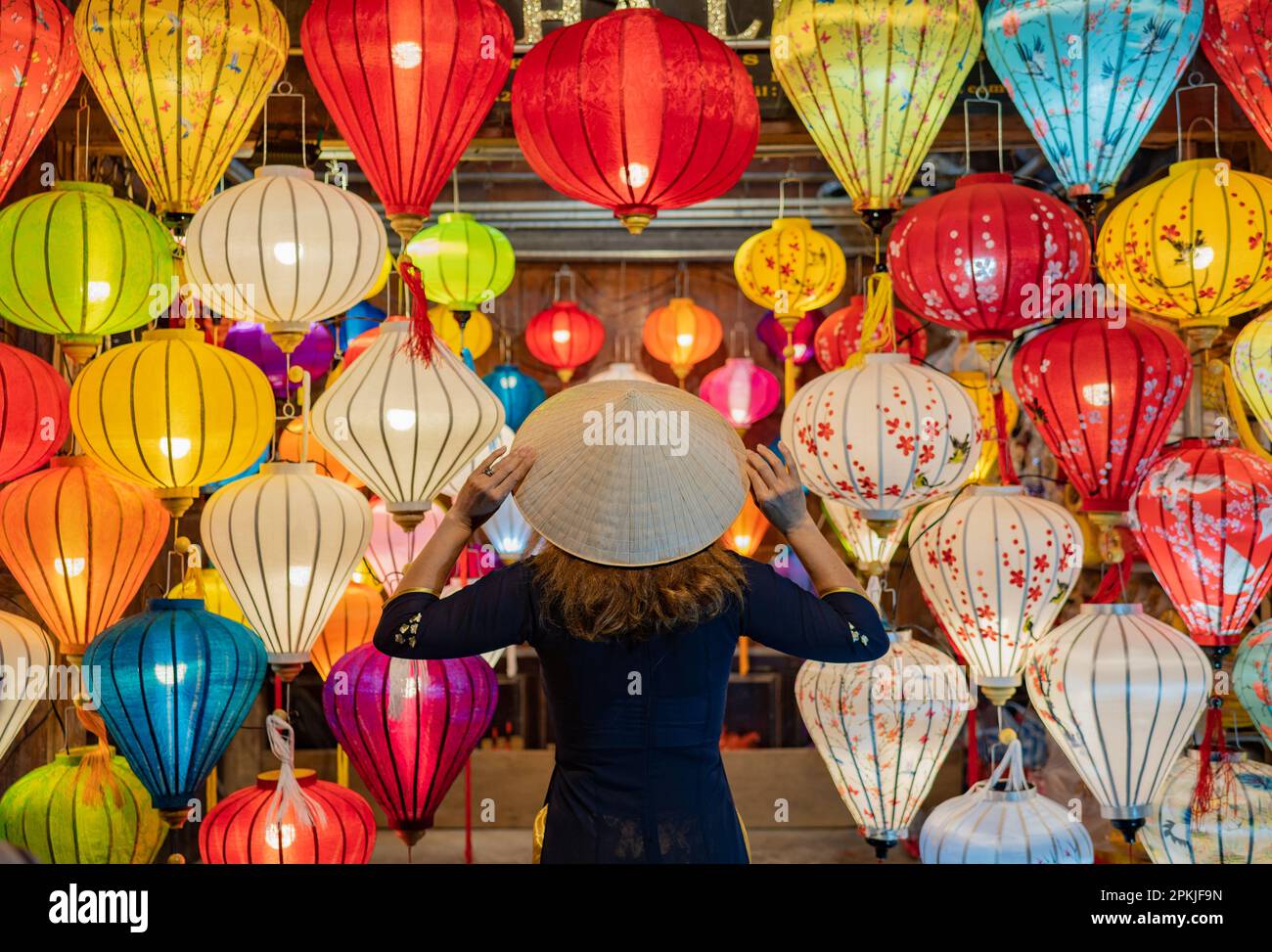 Back view anonymous woman in dress touching Asian conical hat on head ...