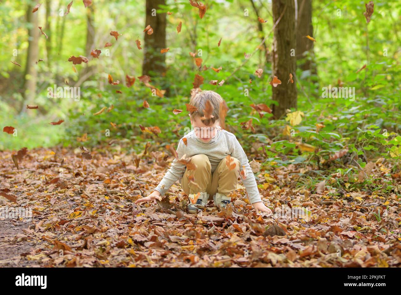 Full length shot of a Little happy boy sitting in a squat throwing ...
