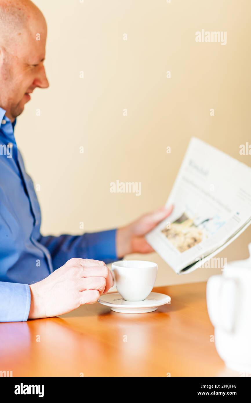 A Best Ager is drinking coffee and reading a newspaper Stock Photo - Alamy
