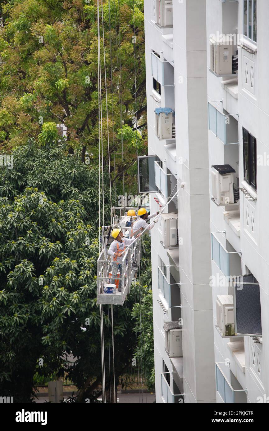 Vertical view of three painting specialists in elevator scaffold ...