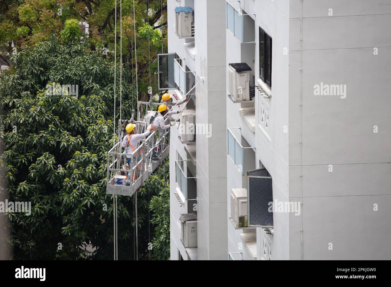 Three painting specialists on elevator scaffold working at height to re ...