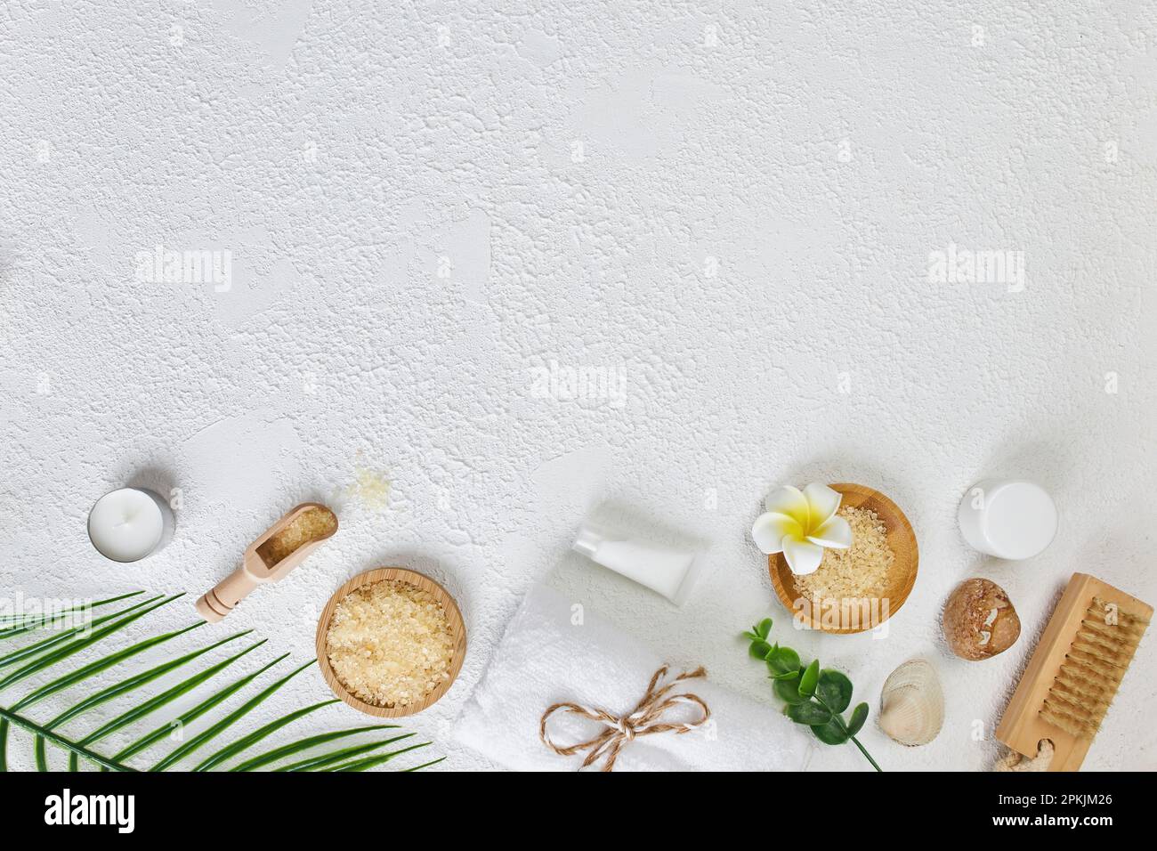 Spa treatment concept. Natural spa cosmetics products, sea salt, massage brush, towel, tropic ...