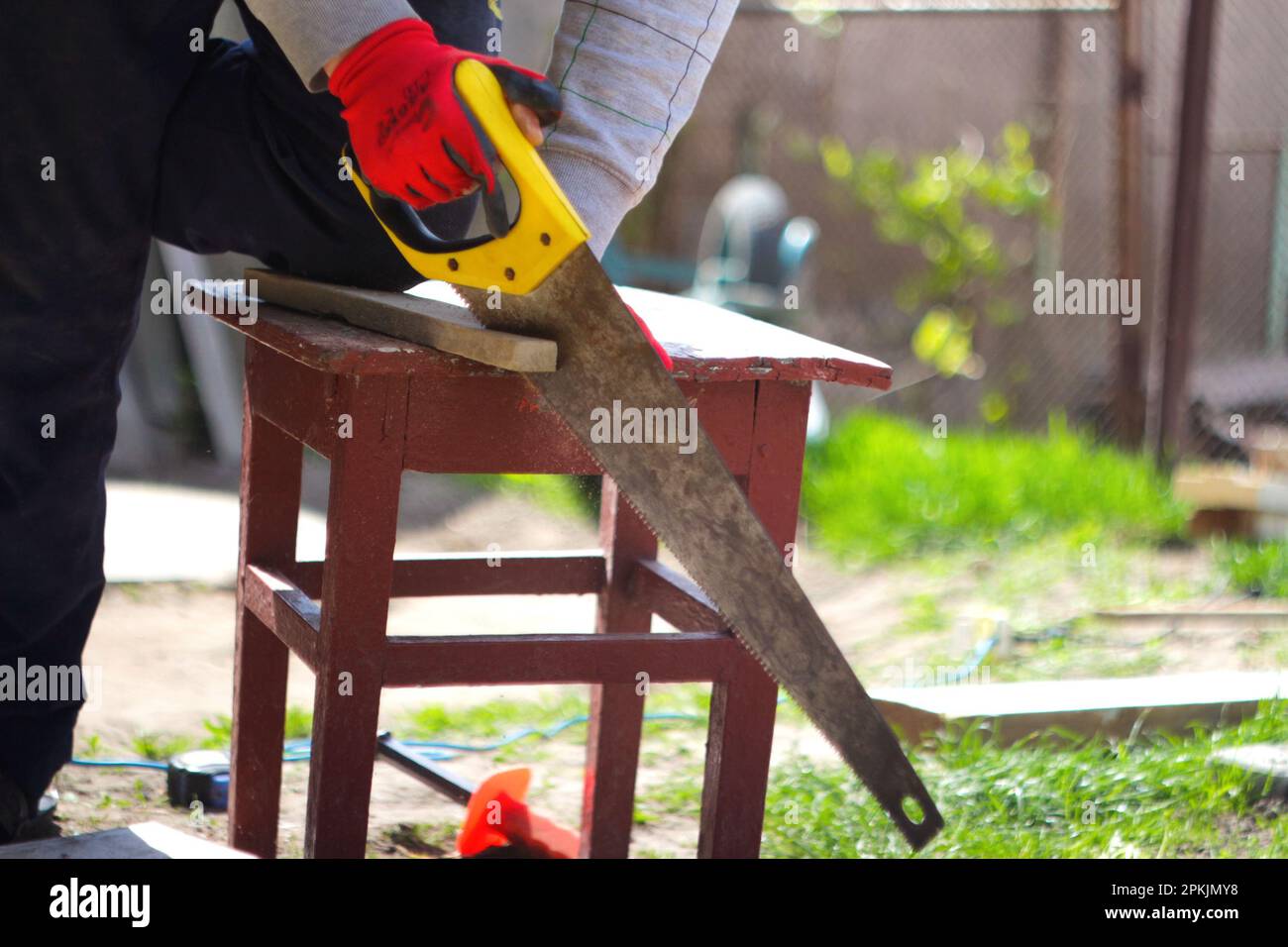 Man cut with yellow saw outside. Defocus saw on blurred background ...