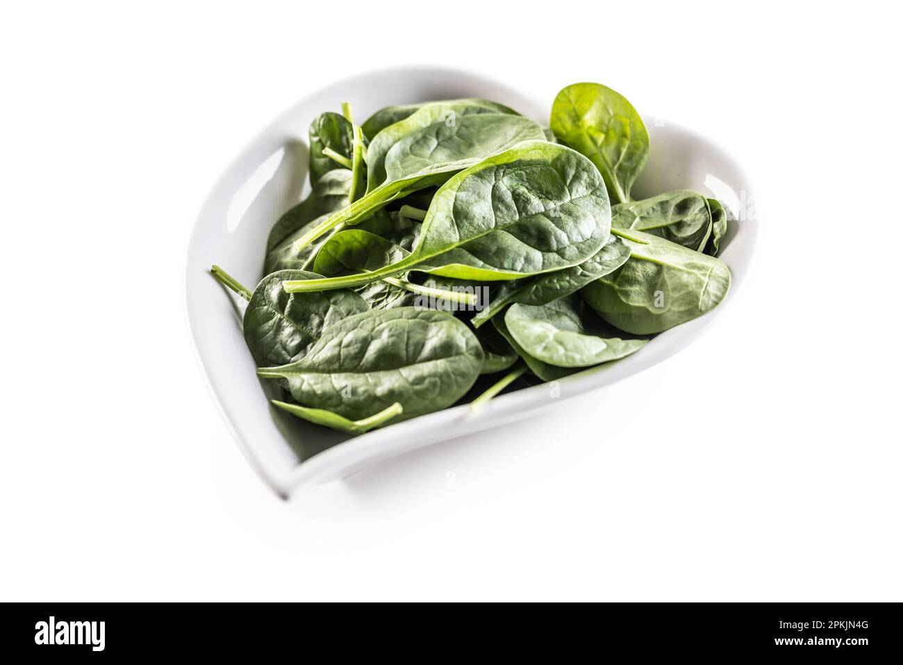 Heart-shaped bowl of young spinach leaves on an isolated white ...