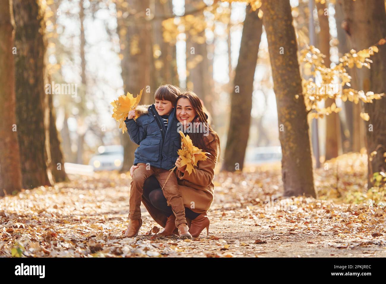 Front view. Mother with her son is having fun outdoors in the autumn ...