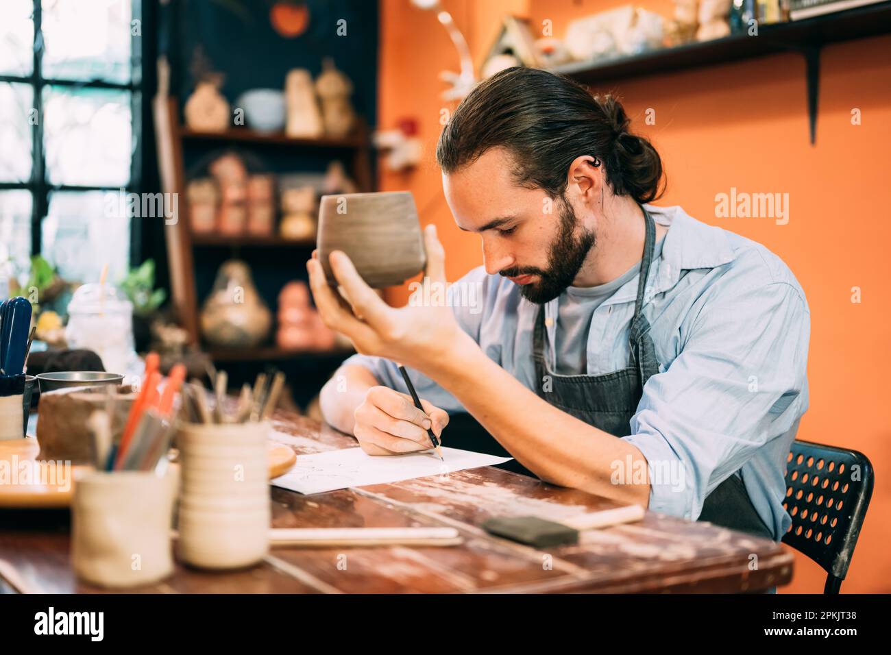 Craftsman potter making jug of clay on potter wheel circle in workshop ...