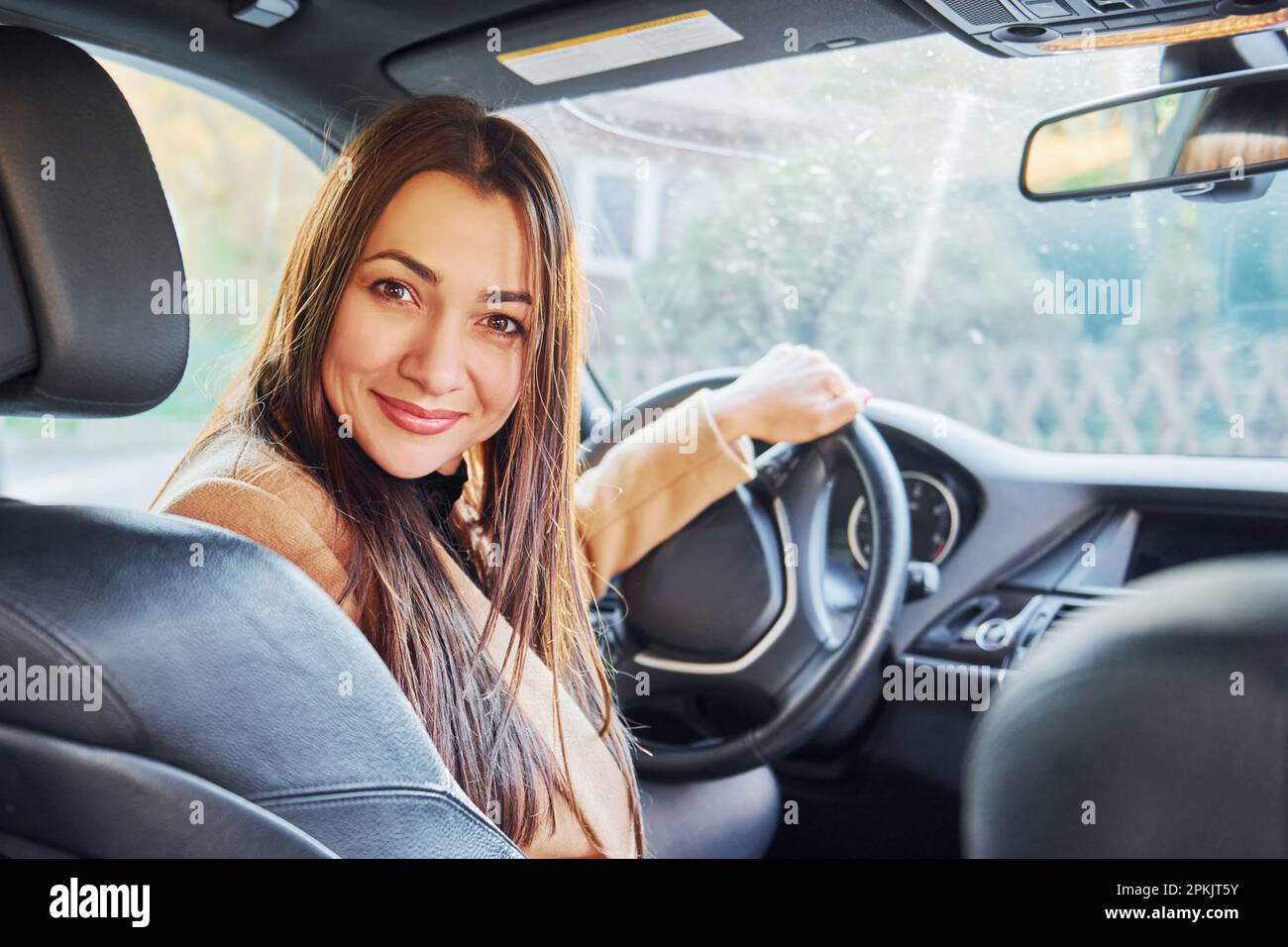 Vehicle interior. Woman is sitting in modern black colored automobile ...