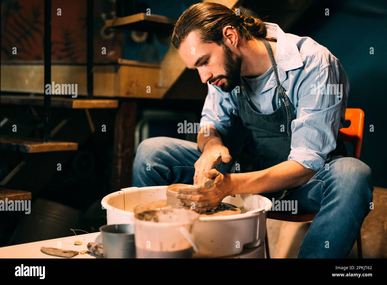 Craftsman potter making jug of clay on potter wheel circle in workshop ...