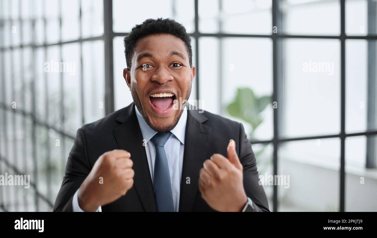Photo of a young excited guy rejoicing in his luck in a black suit ...