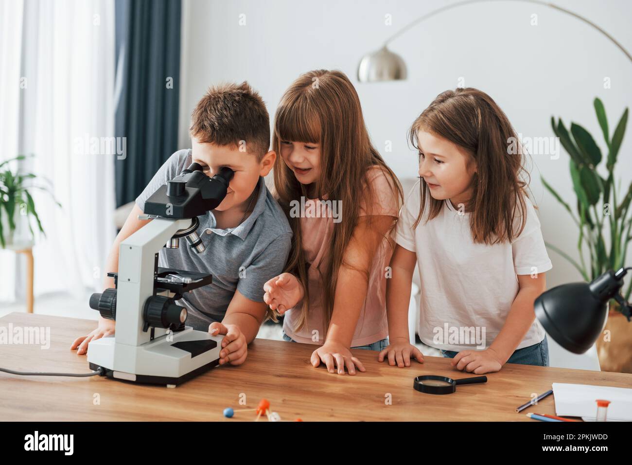 Using microscope. Kids having fun in the domestic room at daytime ...