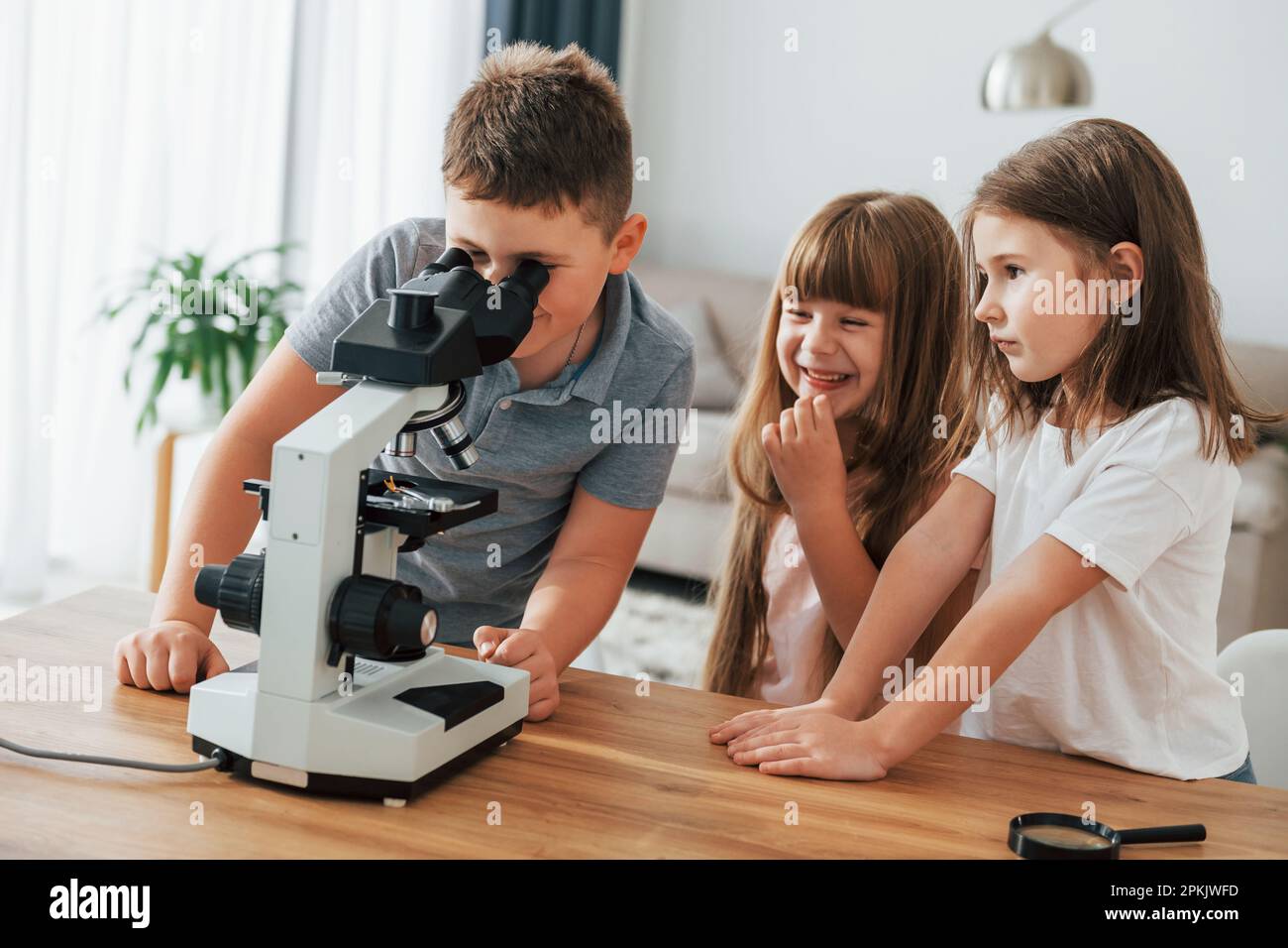 With microscope. Kids having fun in the domestic room at daytime ...