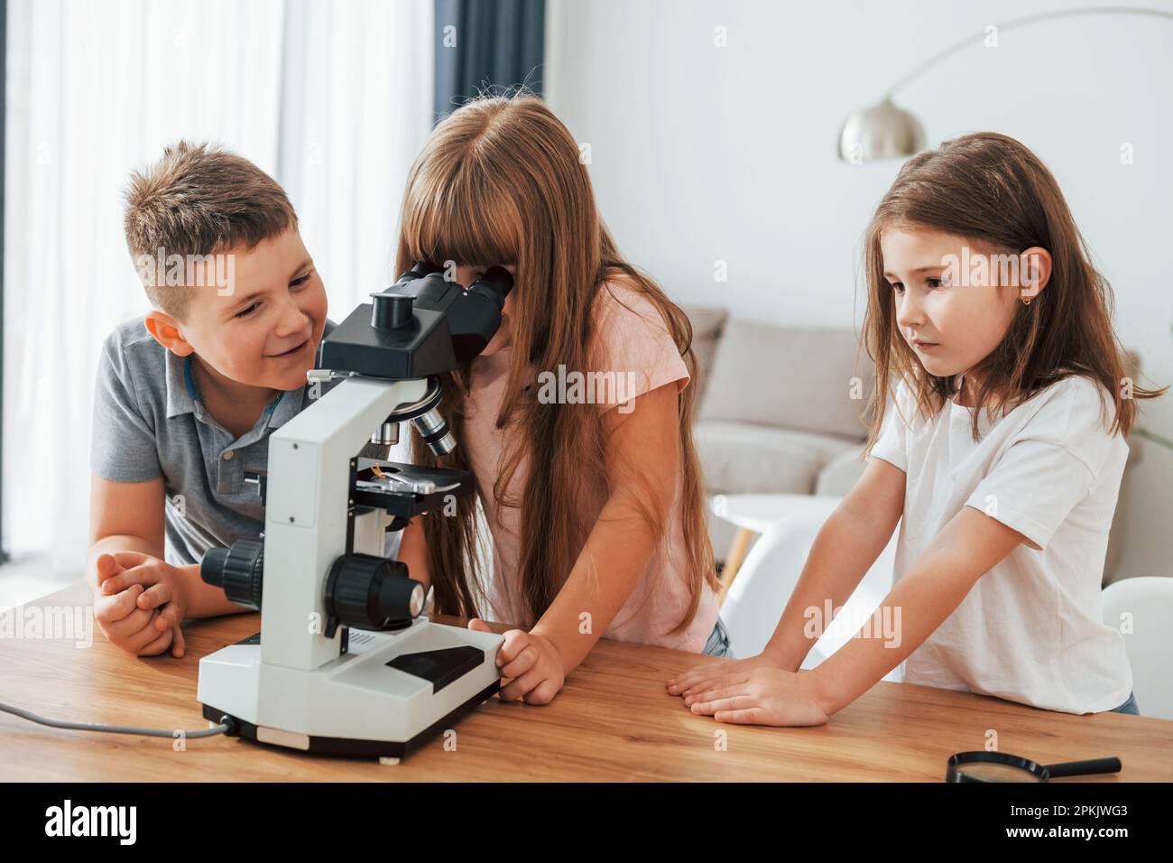 Using microscope. Kids having fun in the domestic room at daytime ...
