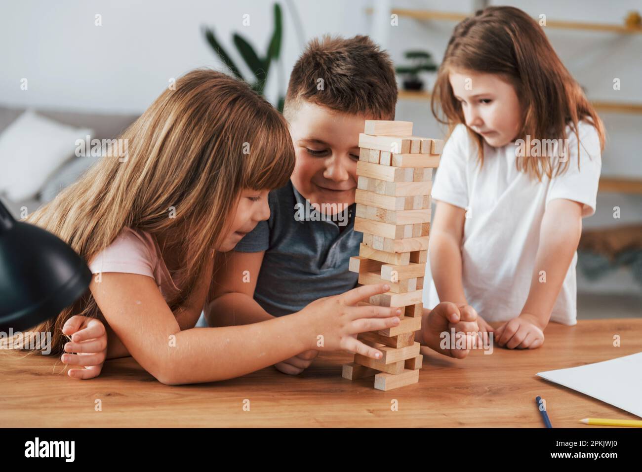 Jumbling tower game. Kids having fun in the domestic room at daytime ...