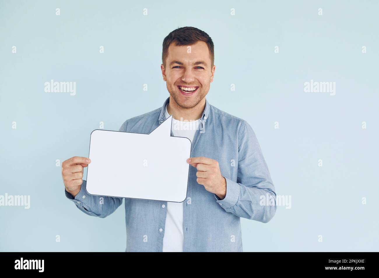 Smiling and having good mood. Man standing in the studio with empty ...